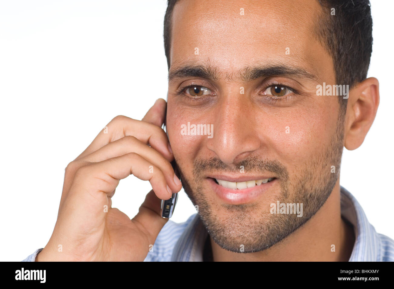 Young Middle Eastern man talking on mobile phone against a white ...