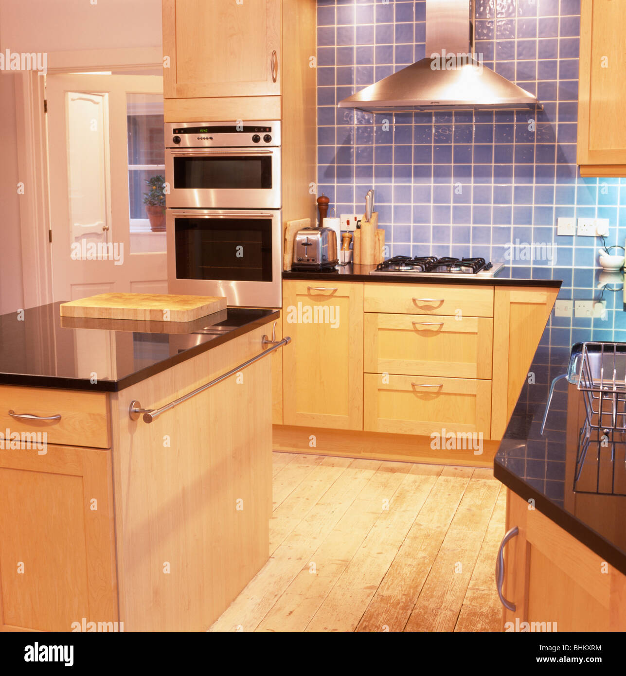 Modern kitchen with blue tiled splash-back and granite-topped island ...