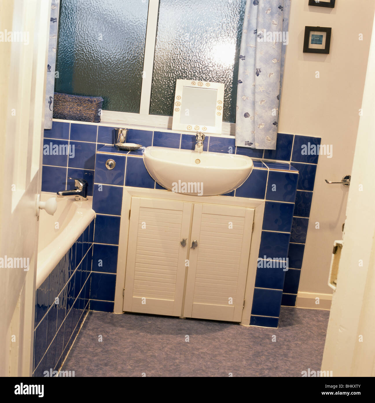 Wall-mounted basin below frosted glass window in economy-styled ...