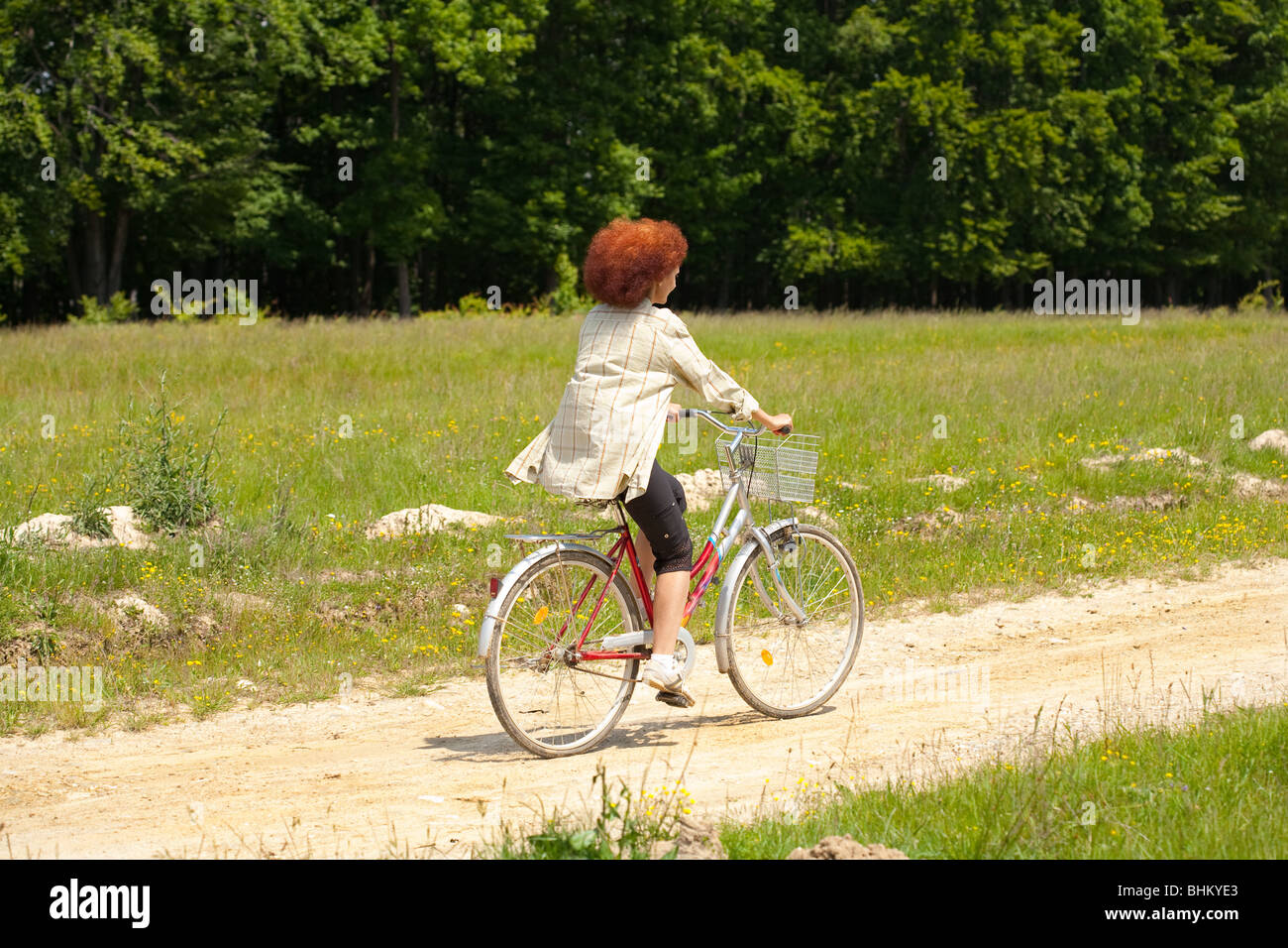 Young woman riding a bike on a country road Stock Photo - Alamy