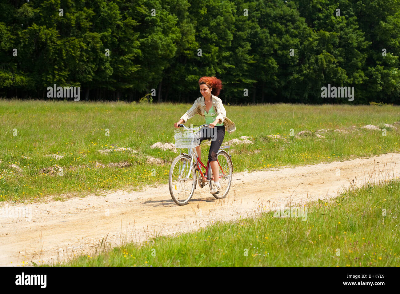Young woman riding a bike on a country road Stock Photo - Alamy