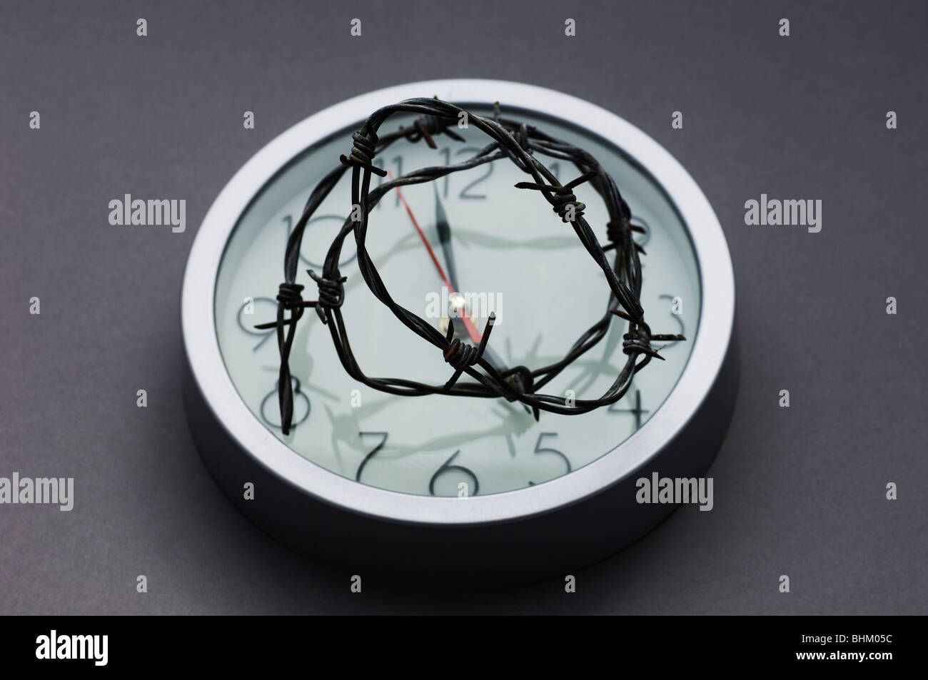 Barbwire over a wall clock Stock Photo - Alamy