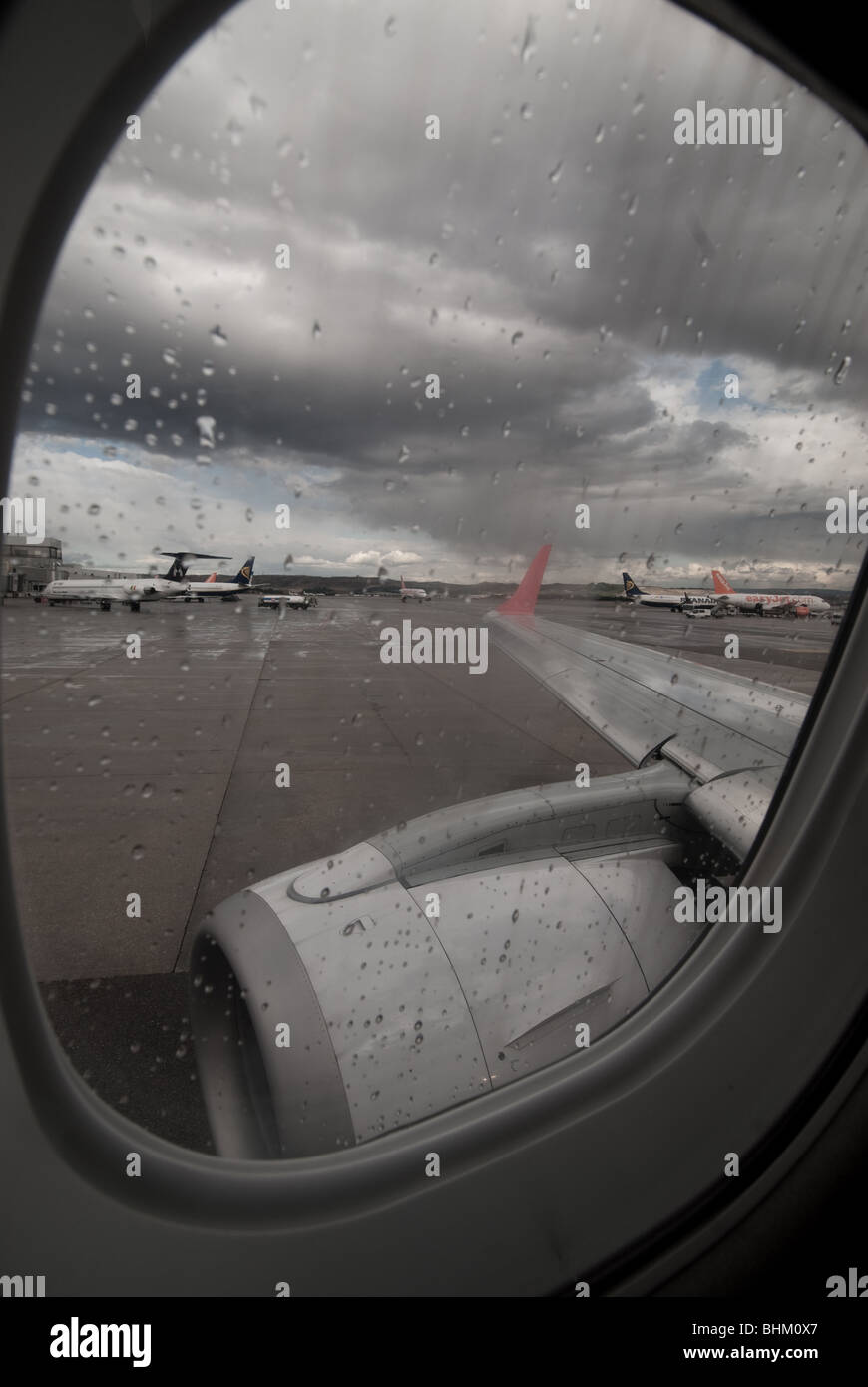 view across runway of taxing aircraft from plane window on a wet day ...