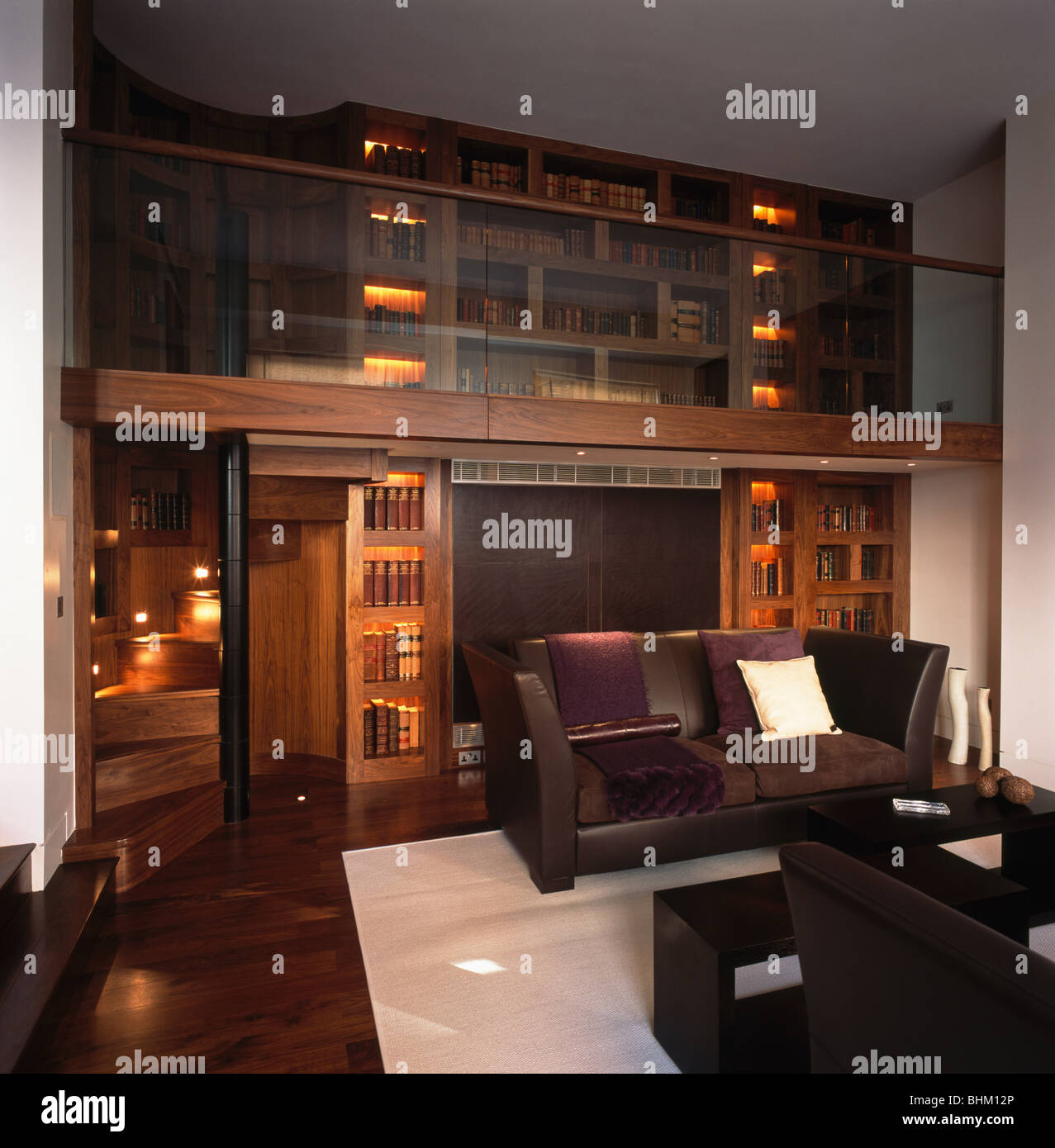 Brown leather sofas in modern double-height library living room with ...