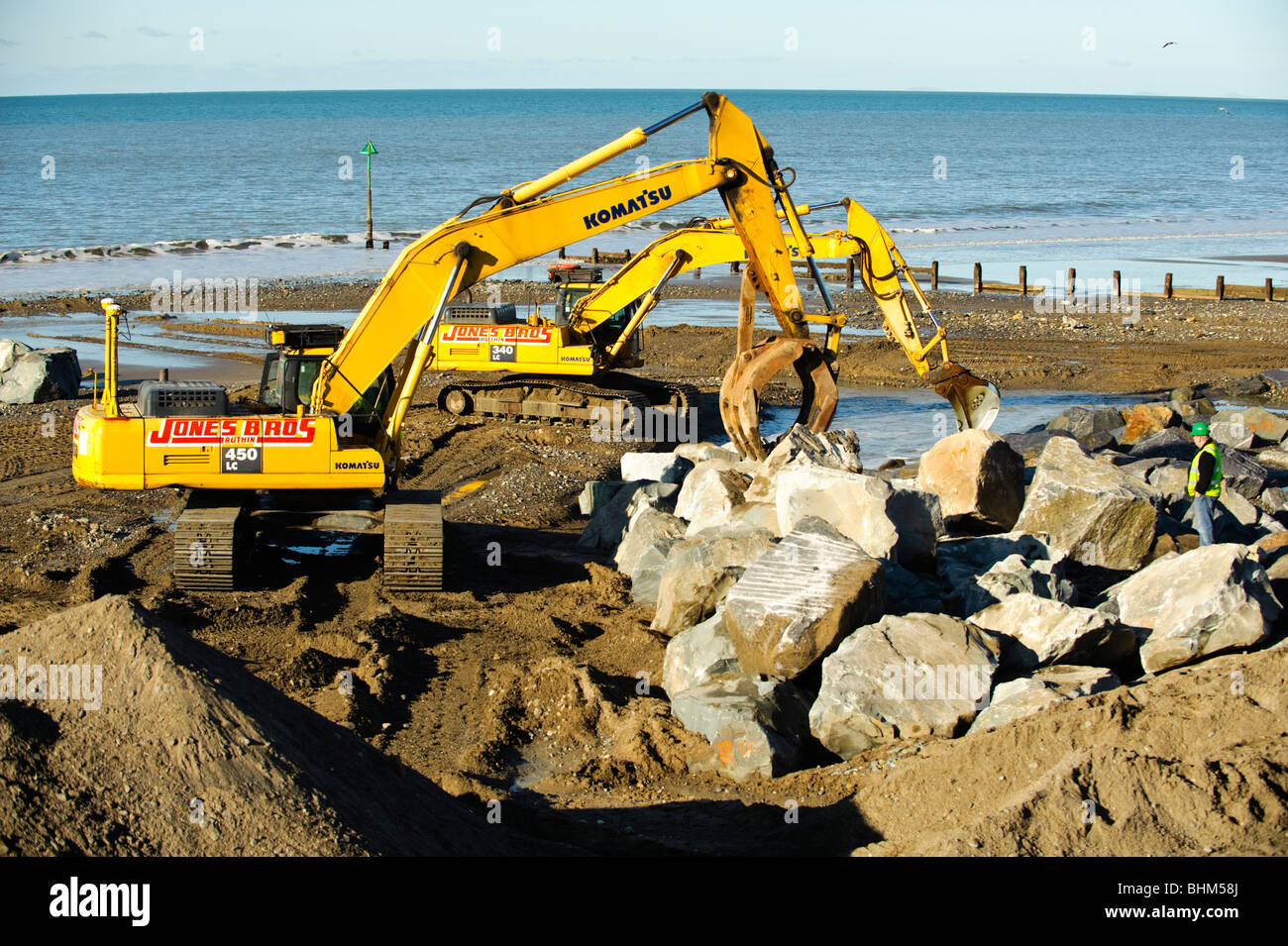 Coastal sea defences being reinforced and repaired with large boulders ...