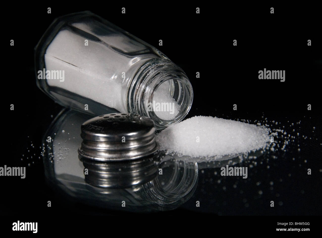 A Glass salt shaker overturned with salt leaking out Stock Photo - Alamy