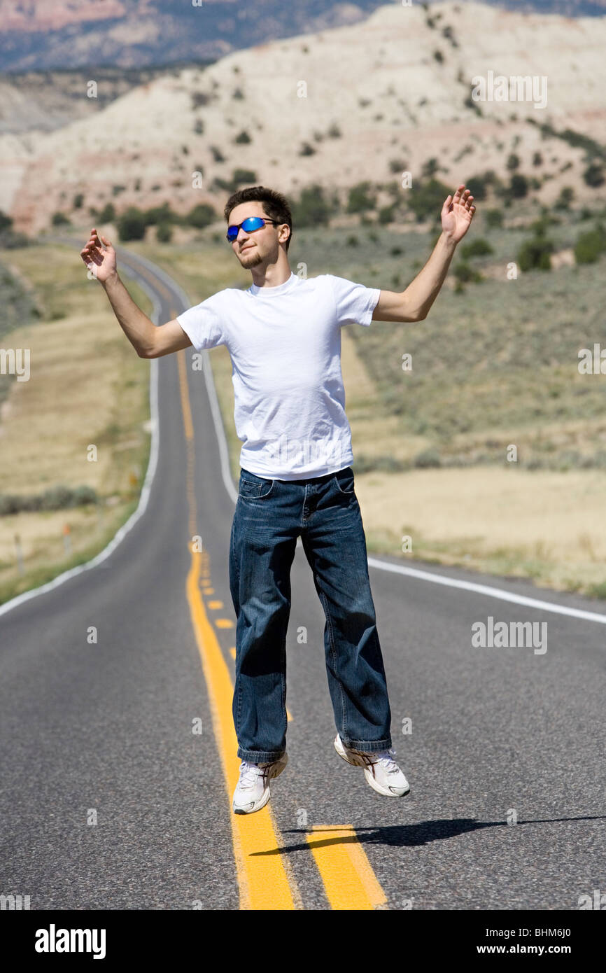Young Man jumping on stretch of empty highway road in Utah Stock Photo ...