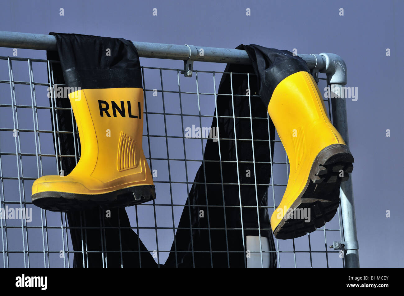 RNLI yellow rubber boots over fence Stock Photo - Alamy