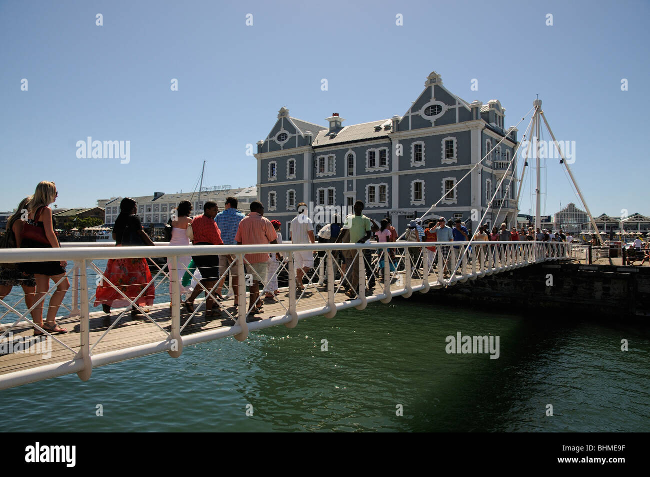 Pedestrians walking on a swing bridge in the V&A Waterfront complex ...