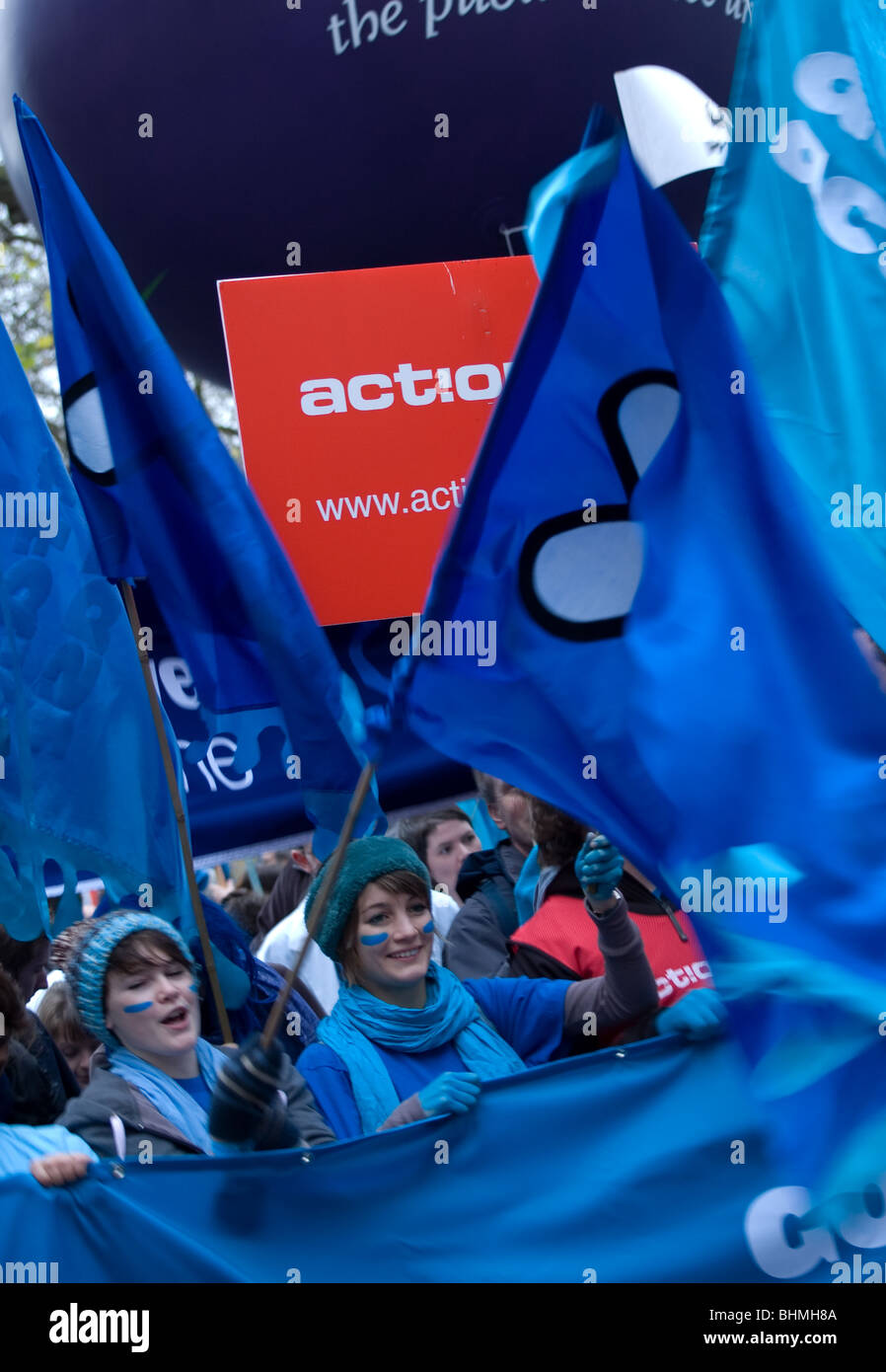 a blue faced protester at the emergency climate rally waving large ...