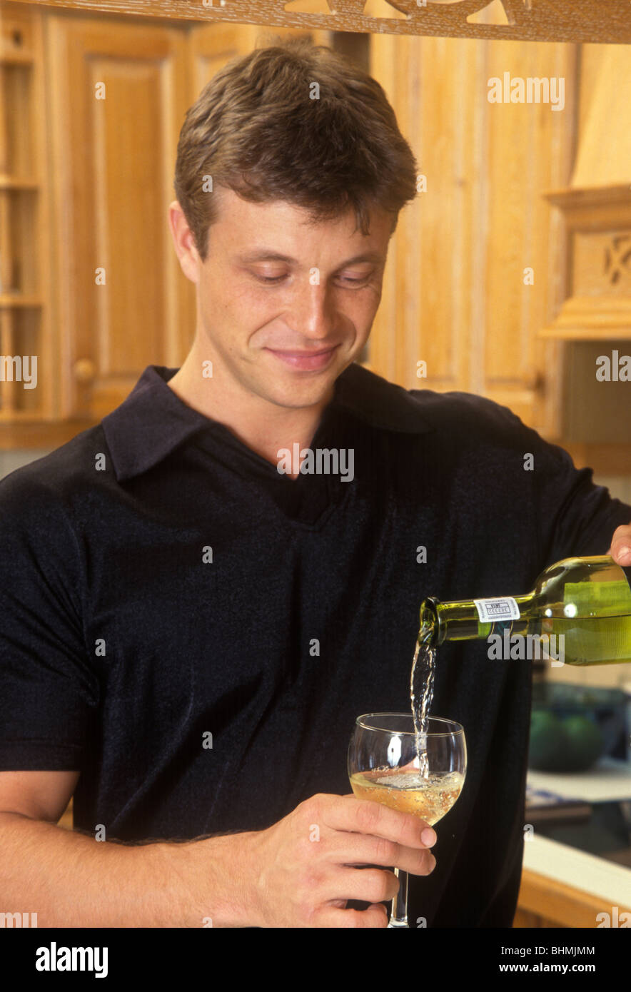 young man pouring a glass of white wine Stock Photo - Alamy