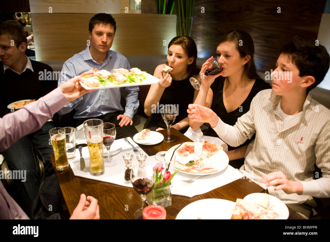 a large group of young people eating in a pizza restaurant Stock Photo ...