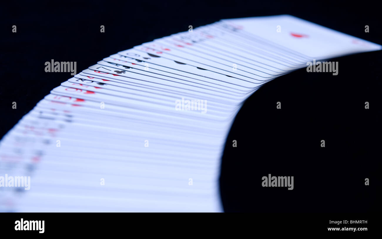 pack of white playing cards layered flat in an arch against a black ...