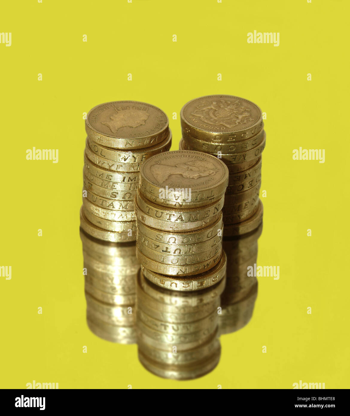 A stack of English one pound coins on yellow background. standing on a ...