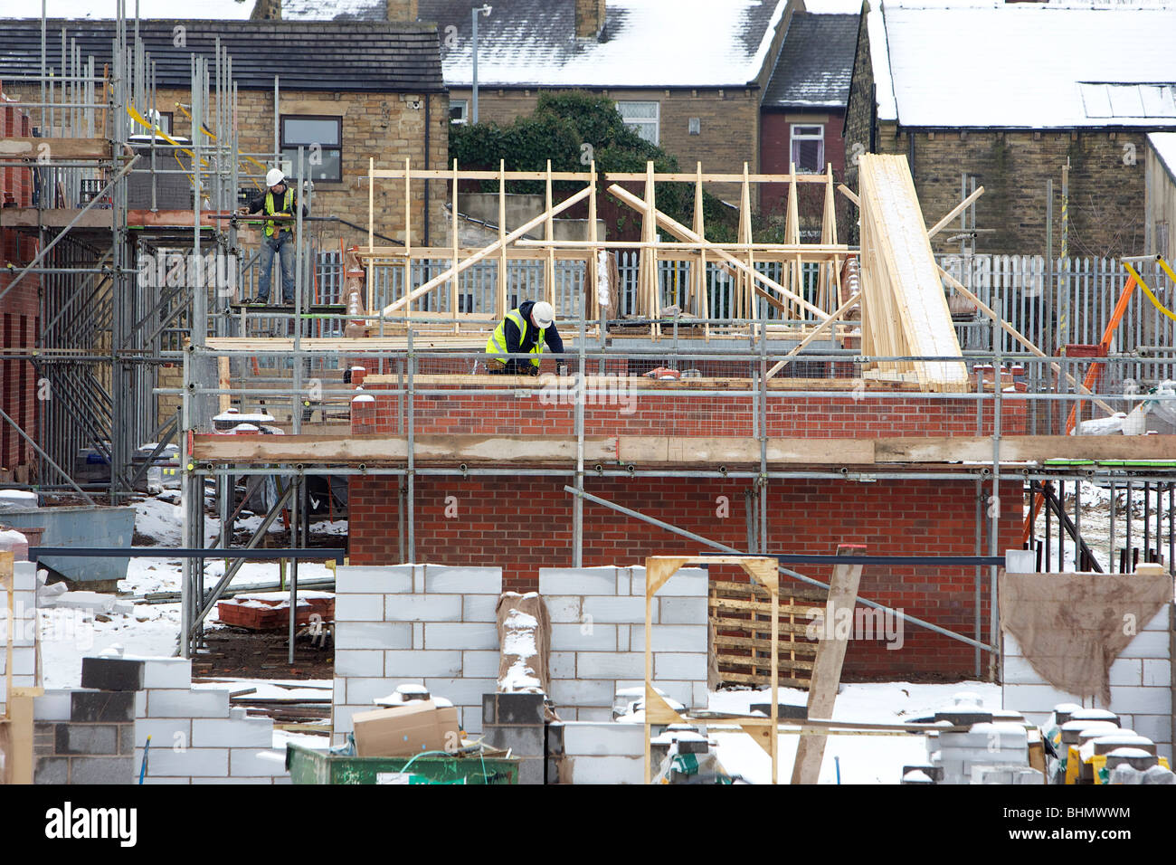 Builders work on scaffolding at a new homes site on a cold winter's ...
