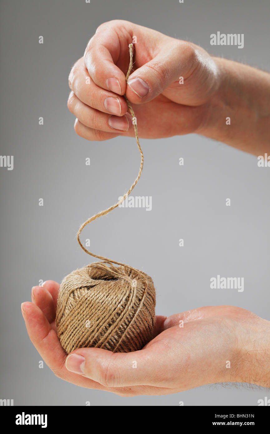 Hand holding a roll of natural fibre string Stock Photo - Alamy