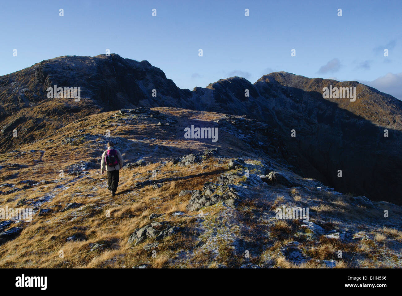 A walker climbs towards Am Bodach, a Munro on the Aonach Eagach ridge ...