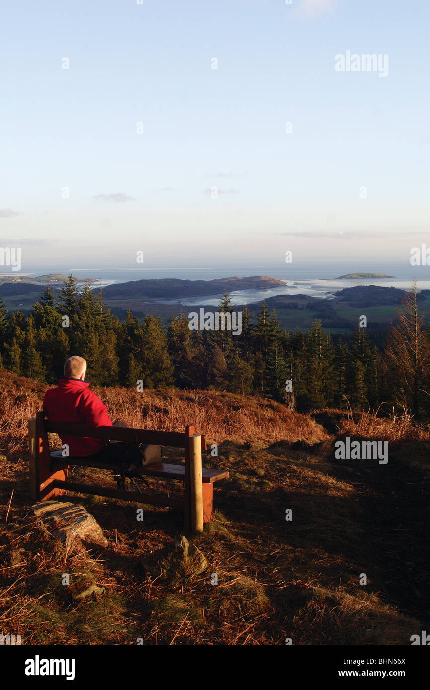 A walker below the summit of Screel looking across the Solway Firth to ...