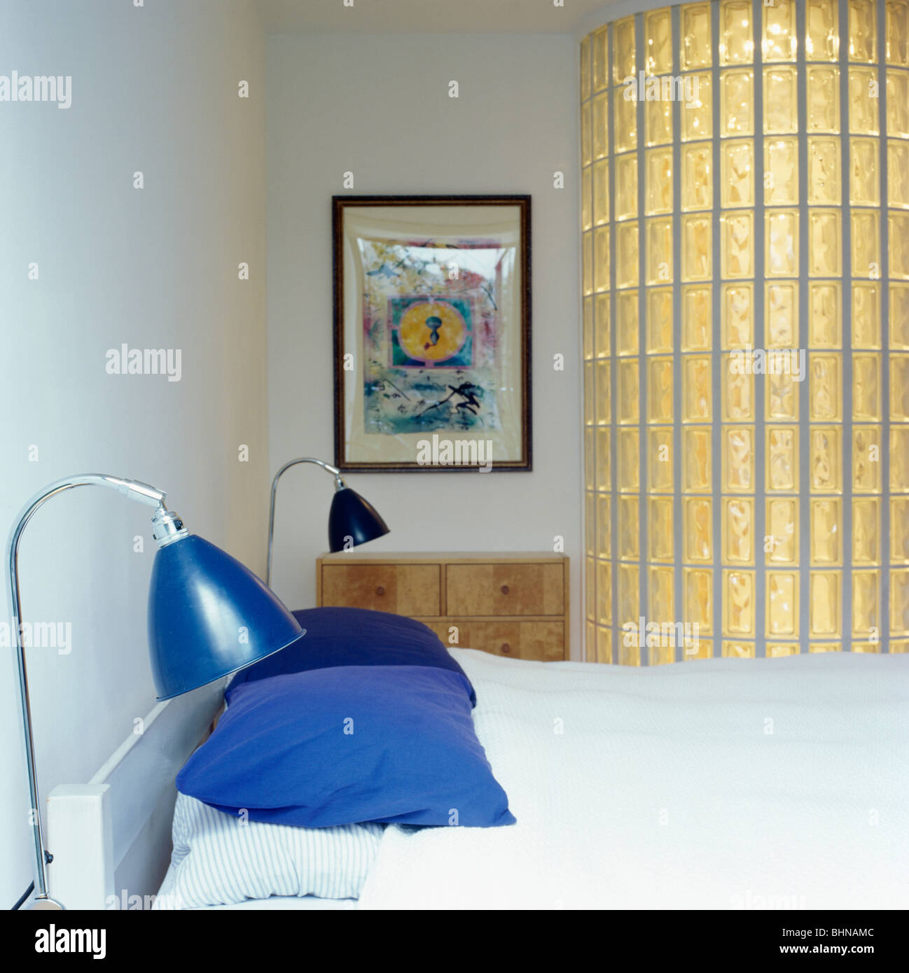 Blue metallic lamps and blue cushions on bed in modern bedroom with ...