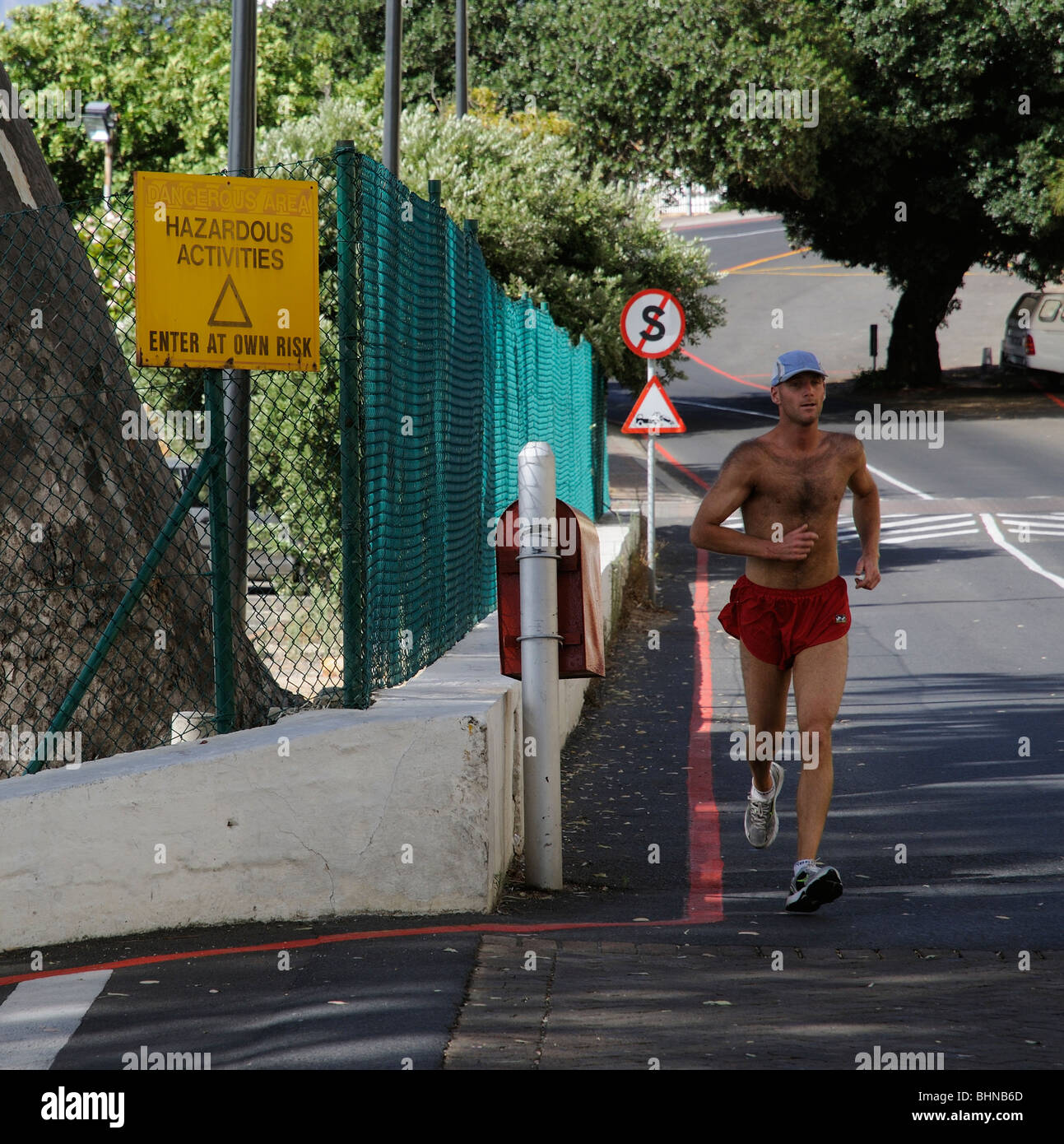 Man running in street & passing a hazardous activities notice on a wire ...