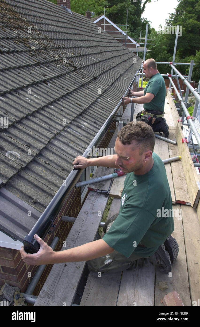 Workmen fit guttering on a council house UK Stock Photo - Alamy