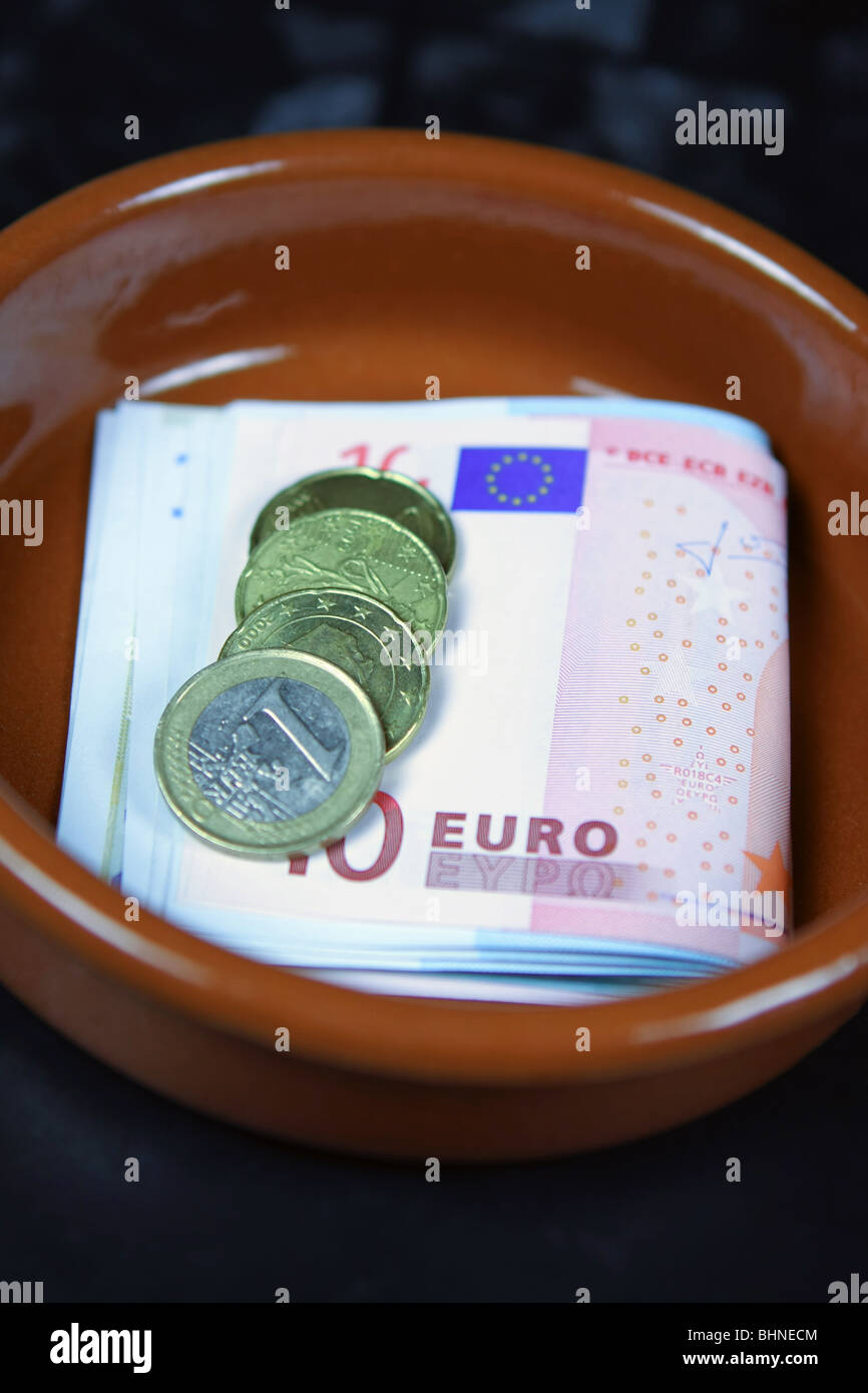 euro notes and coins in a dish on a dark page of an open book Stock ...