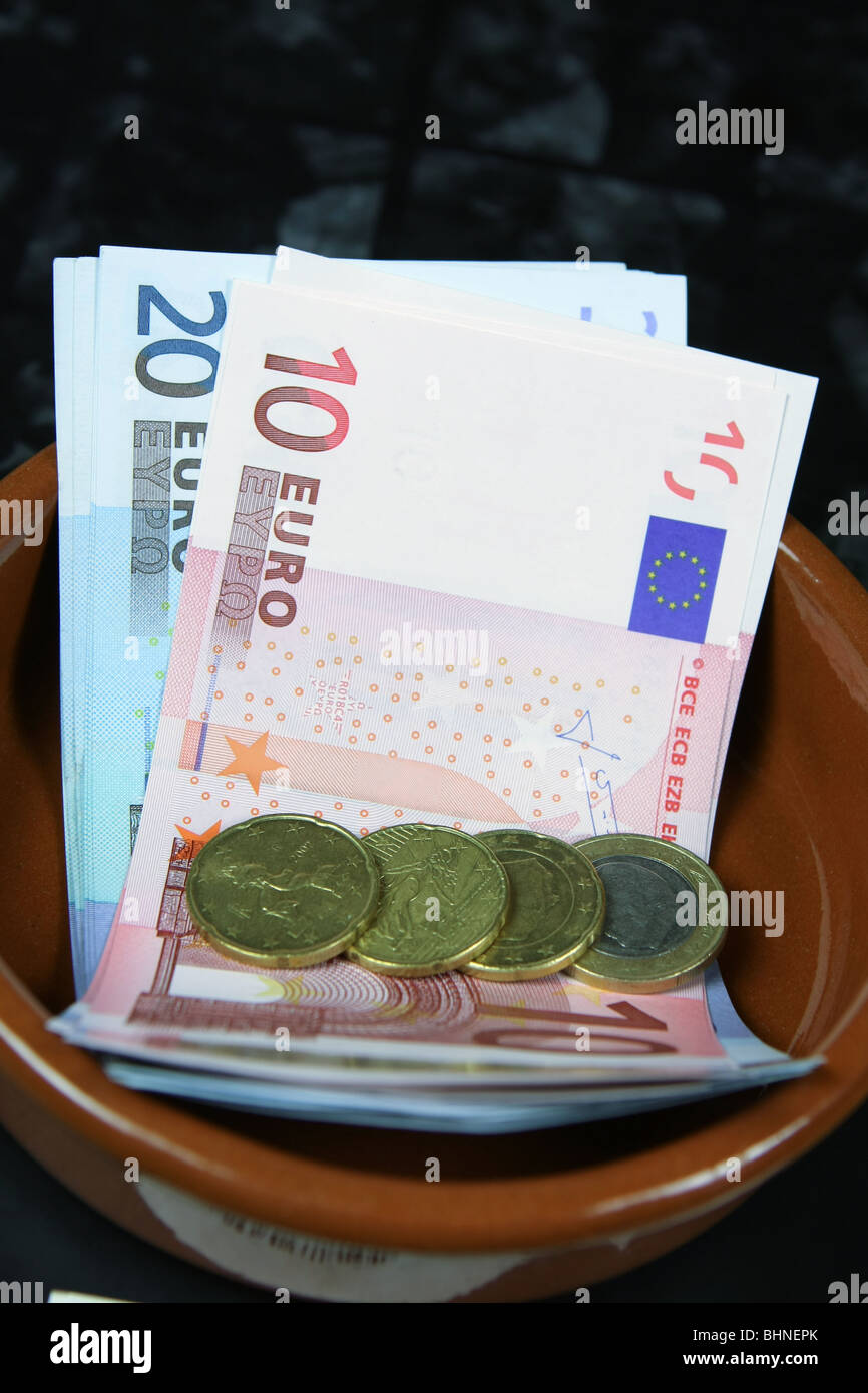 euro notes and coins in a dish on a dark page of an open book Stock ...