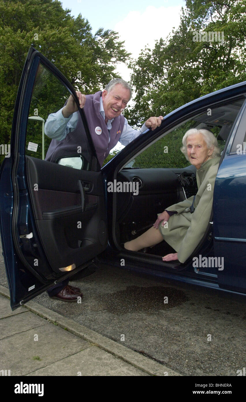 Elderly woman being helped by a male member of the WRVS Stock Photo - Alamy