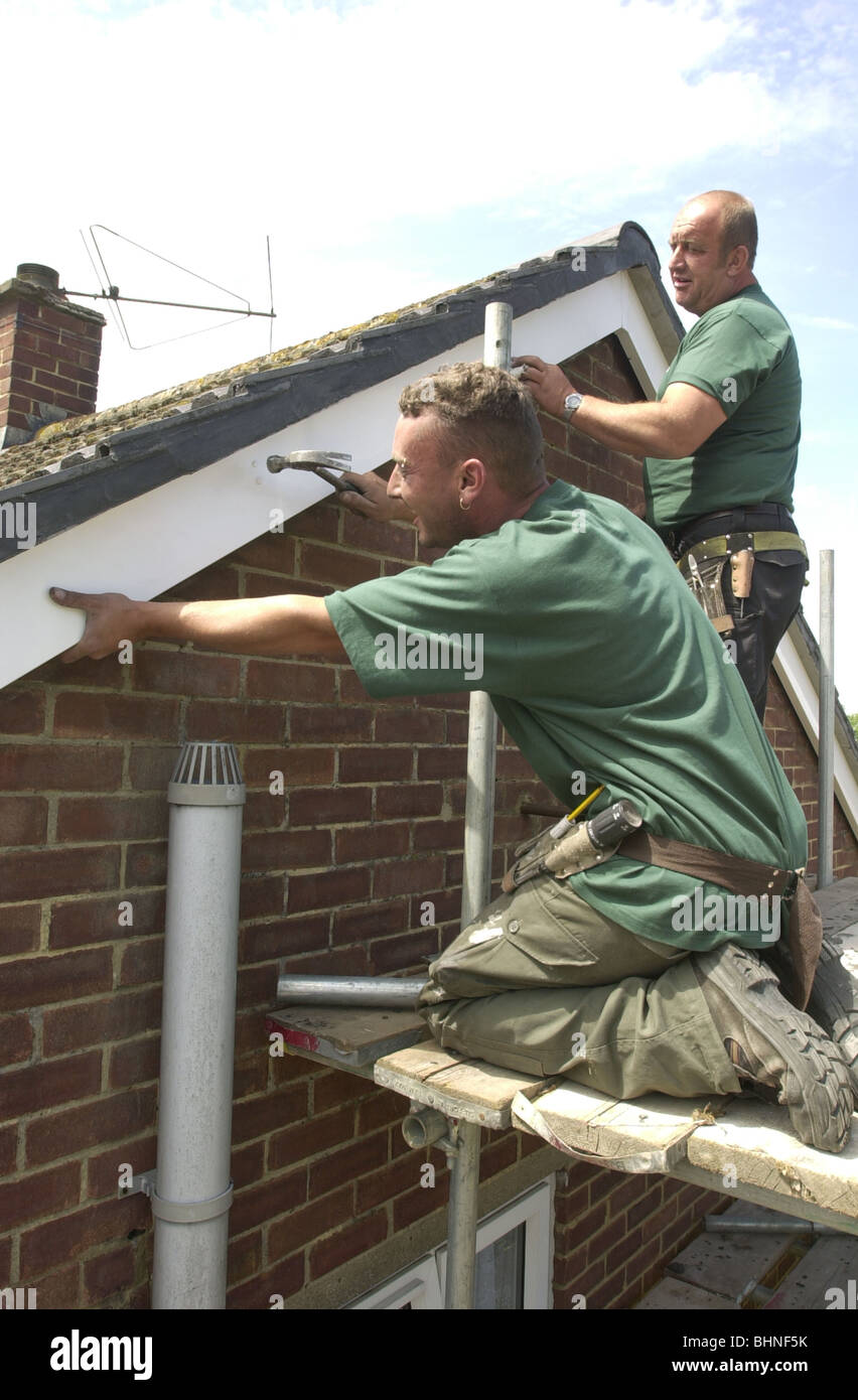 Workmen fit guttering on a council house UK Stock Photo - Alamy