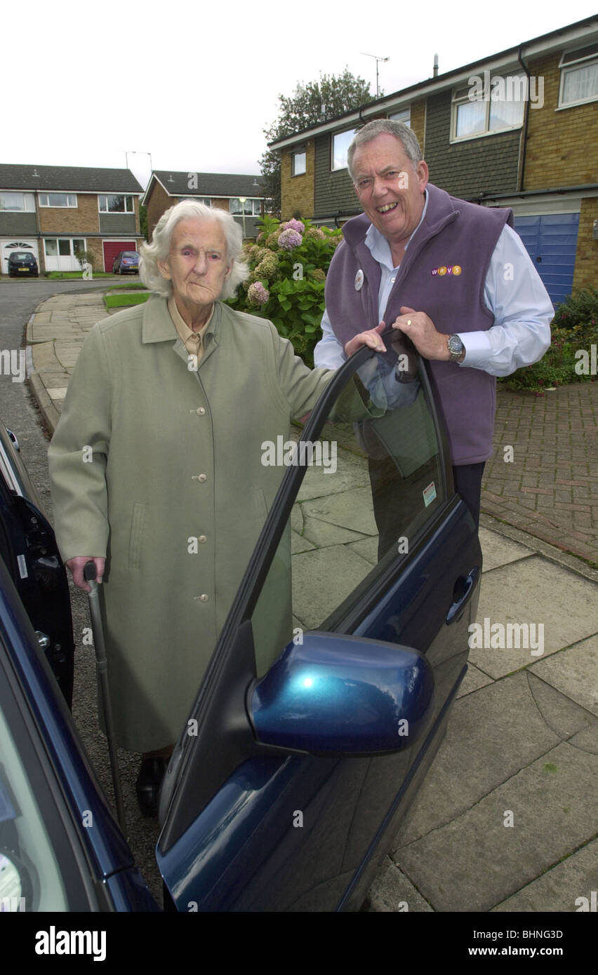 Elderly woman being helped by a male member of the WRVS Stock Photo - Alamy