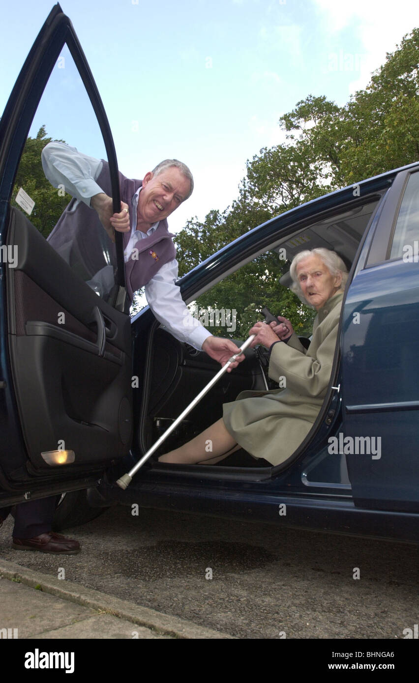Elderly woman being helped by a male member of the WRVS Stock Photo - Alamy