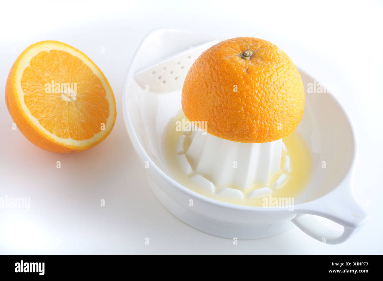 An orange cut in half and in the process of being squeezed in a pottery ...