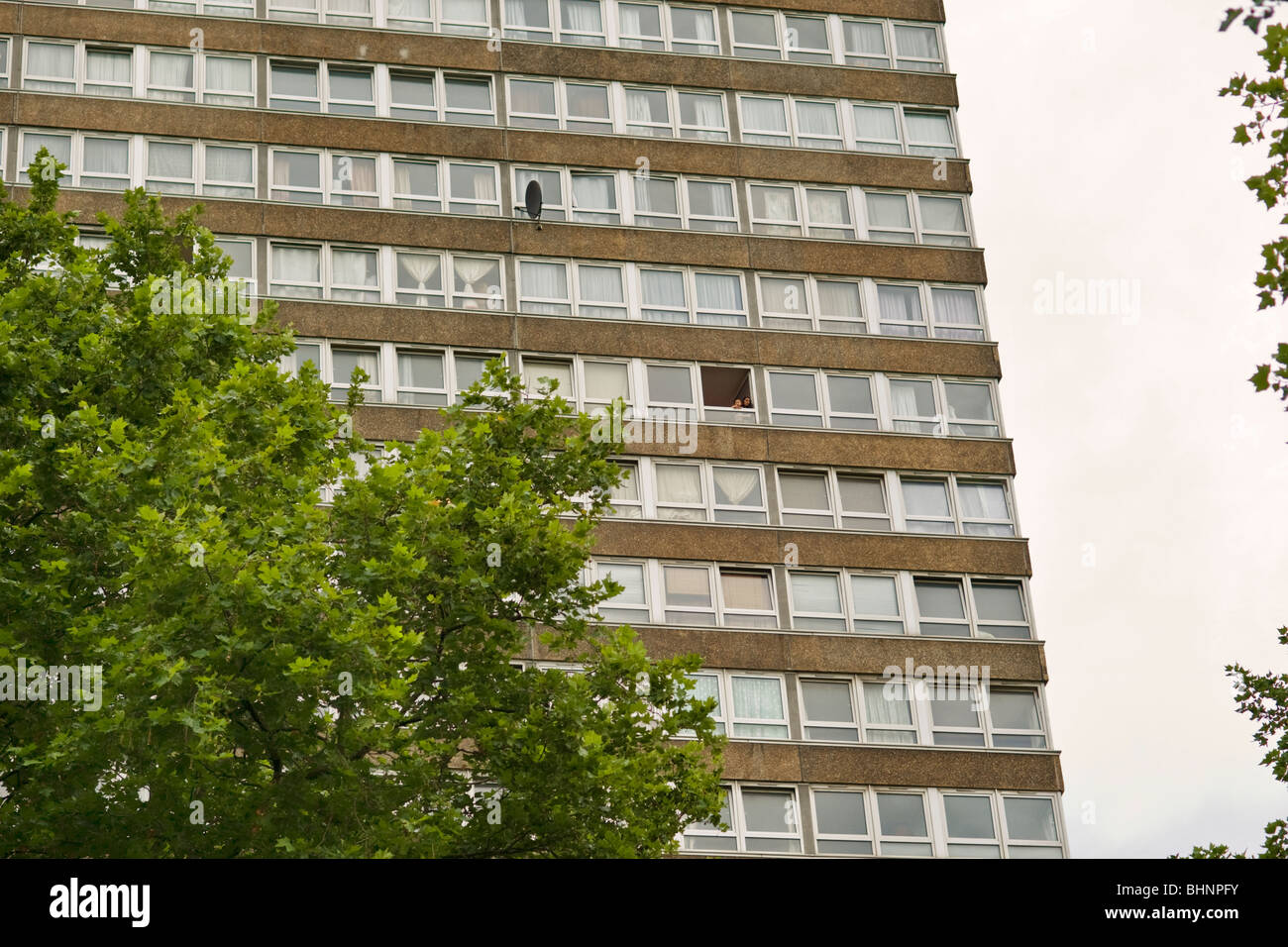 mother with baby sitting by open window of council tower block in ...