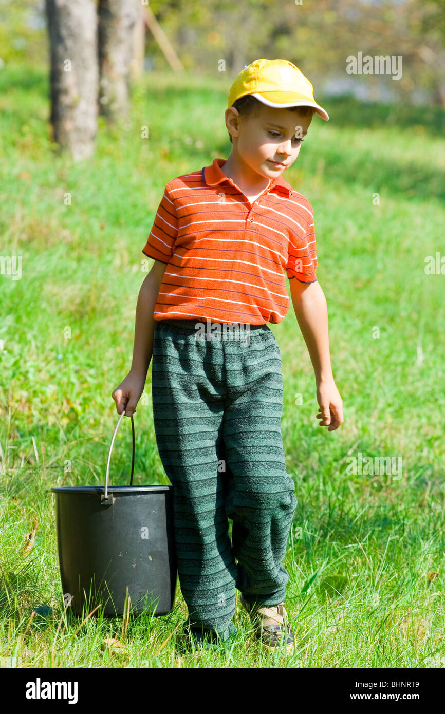 Cute boy with a bucket going to pick up apples in a garden Stock Photo ...