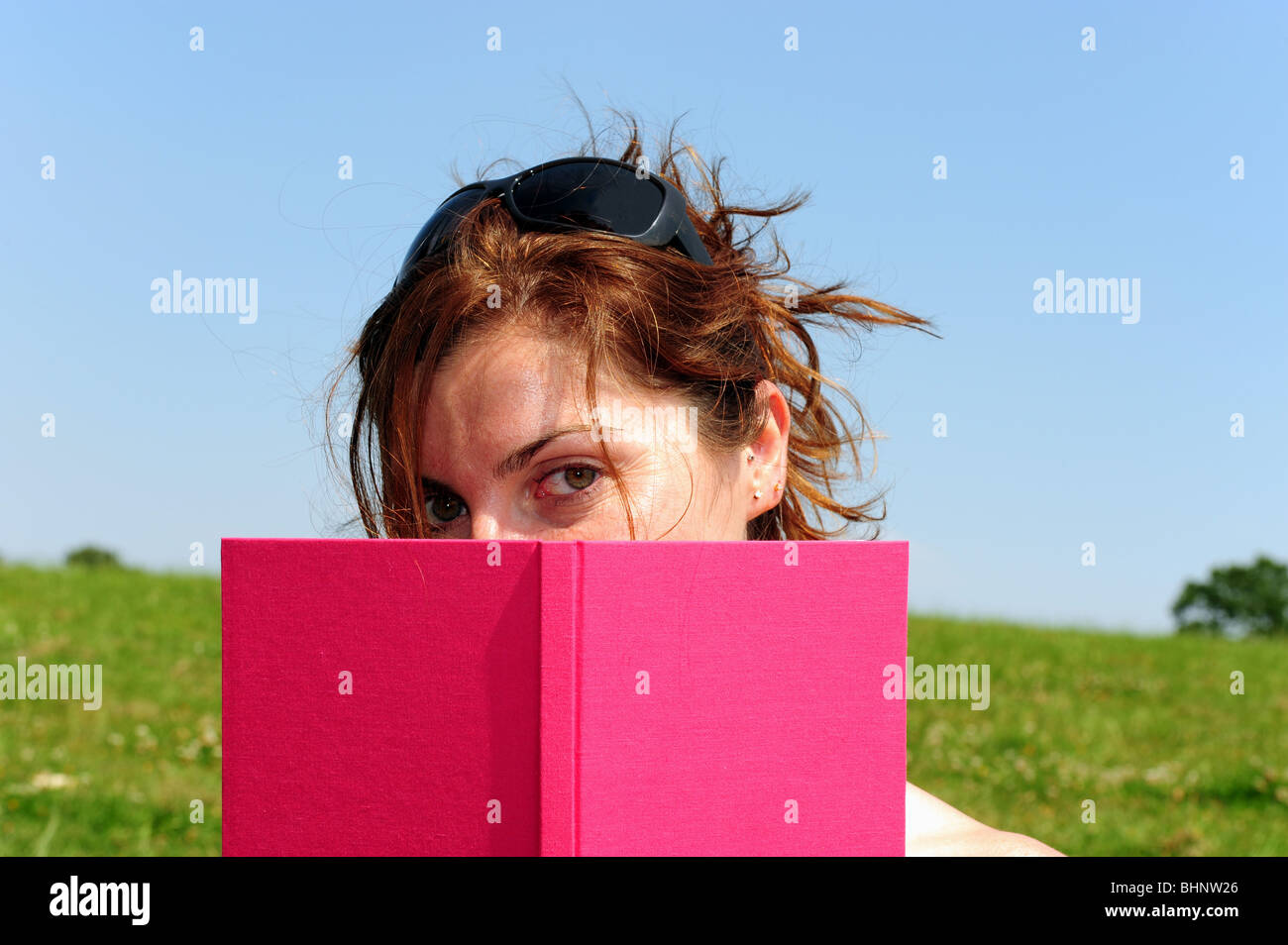 female looks over a book in the park Stock Photo - Alamy