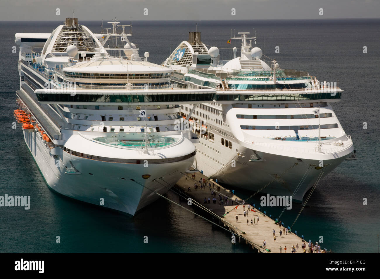 two cruise ships docked side by side at the same pier with passengers ...