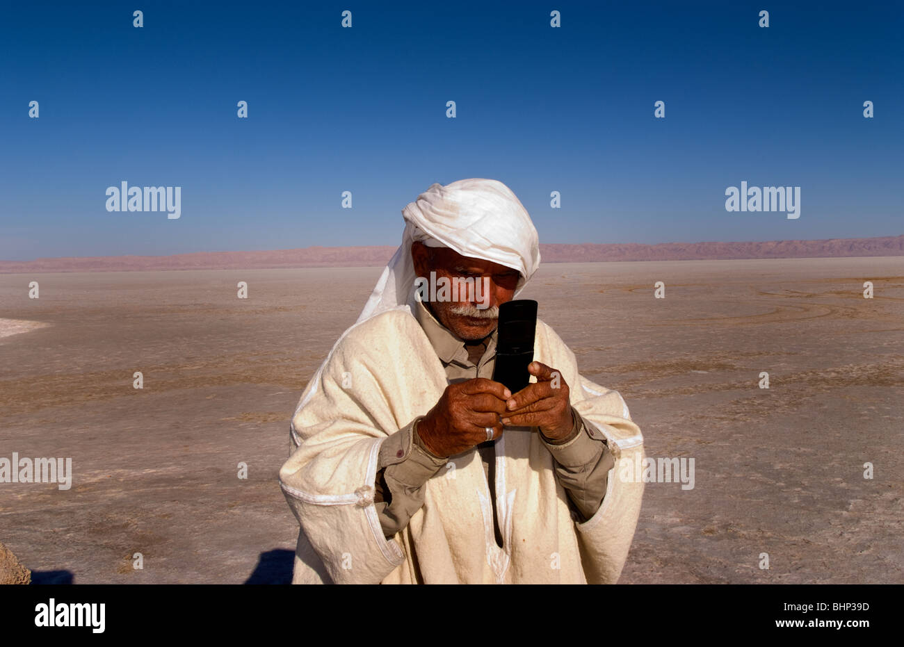 Arab man texting on cell phone Great Dry Salt Lake Chott el Jerid in ...
