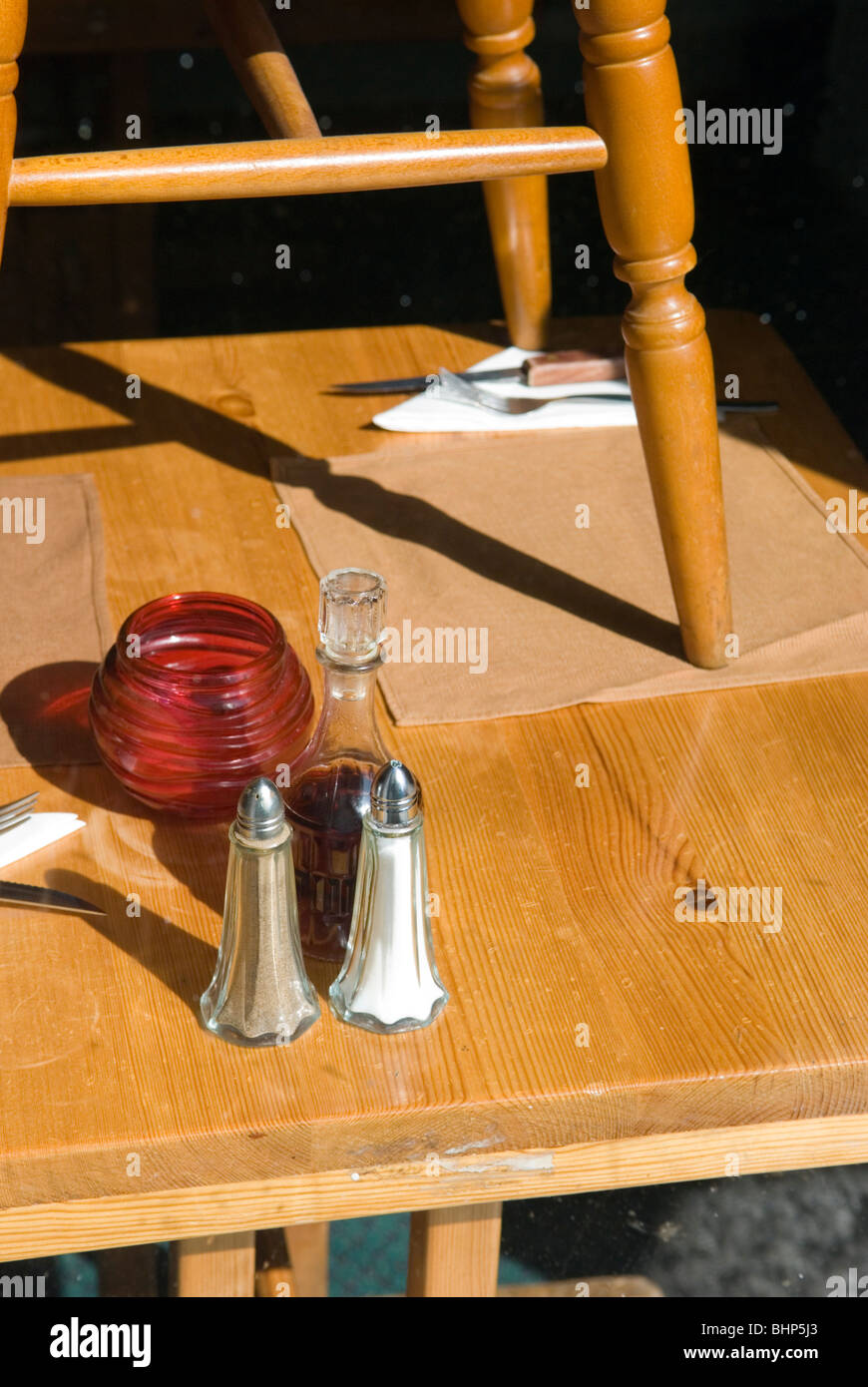 close up of pine table with chair legs, salt, pepper, ashtray and ...