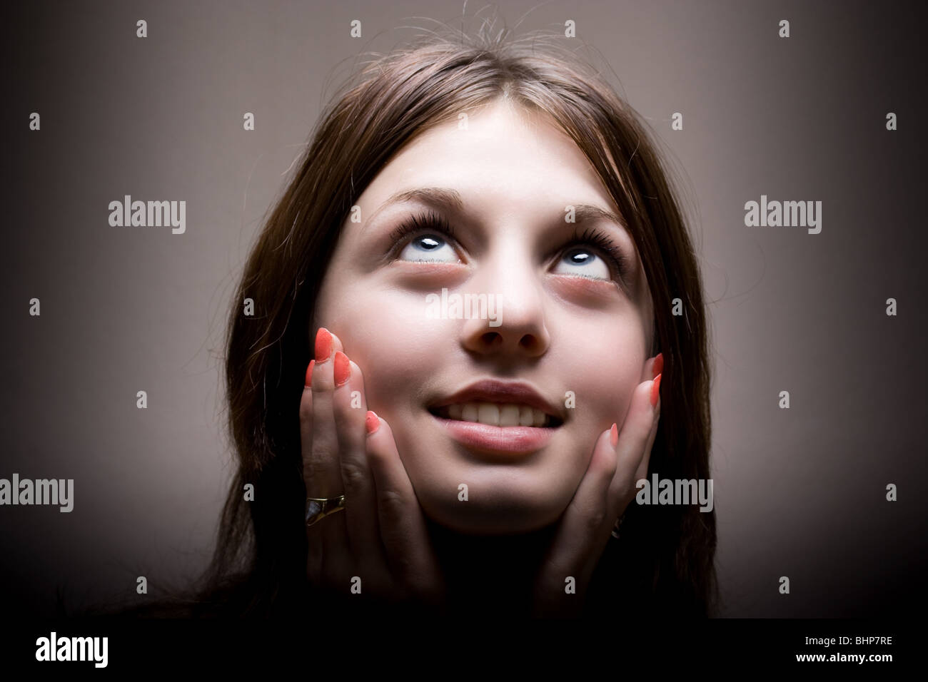 Striking image of a beautiful young woman looking up with light above ...