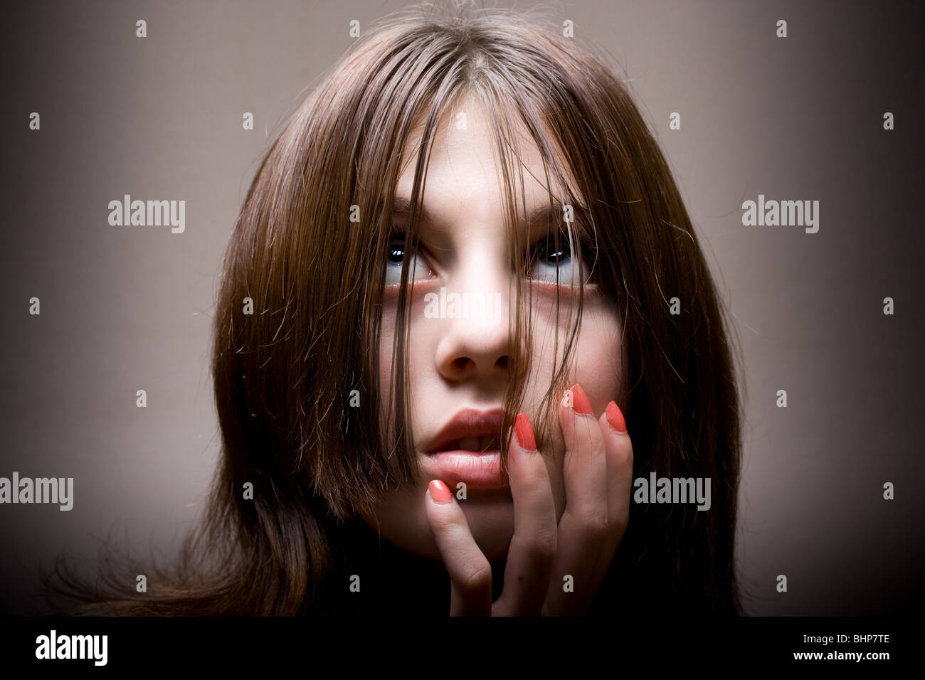 Striking image of a beautiful young woman looking up with light above ...
