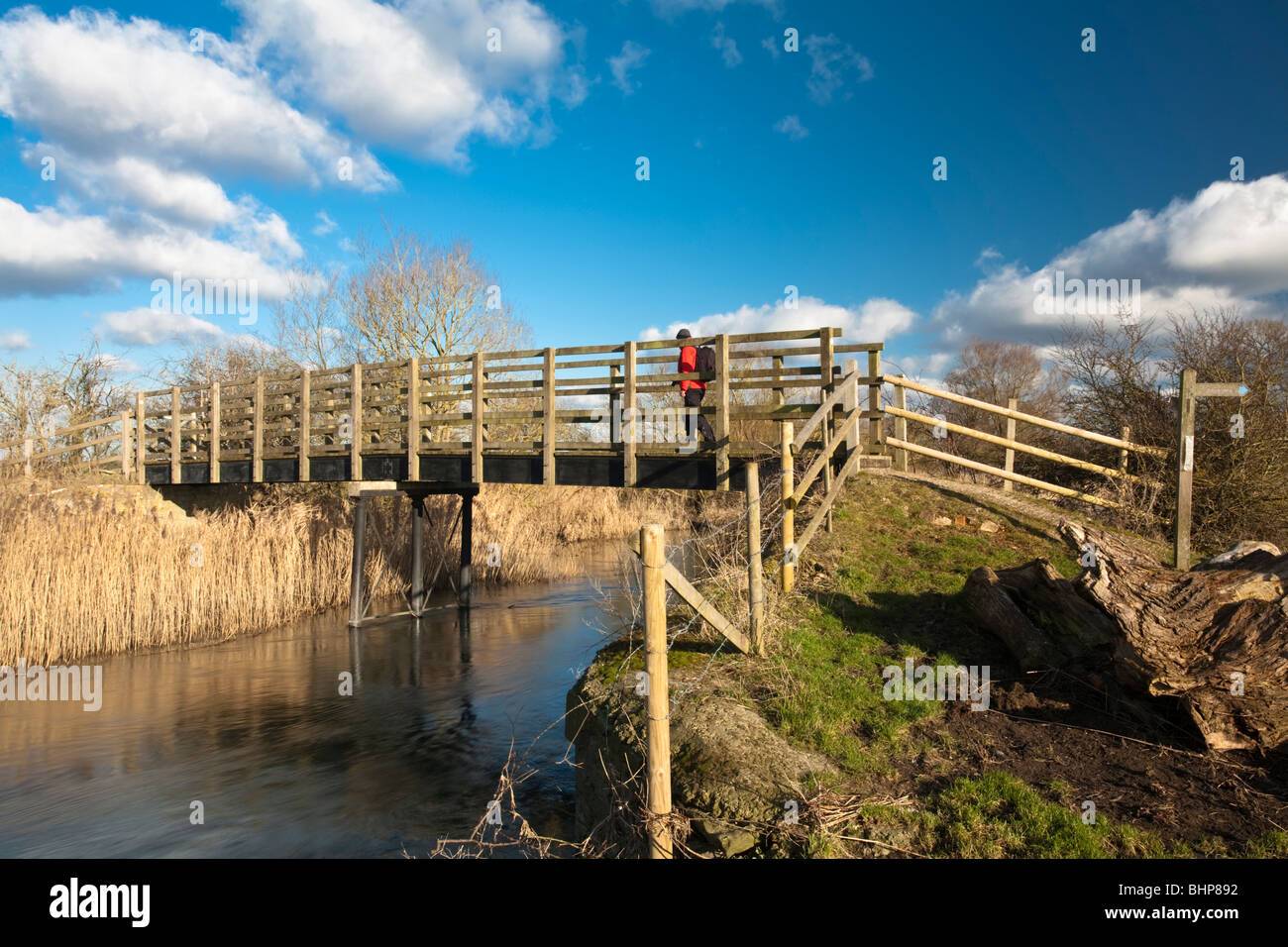 Walker crossing a wooden footbridge over the upper reaches of the River ...