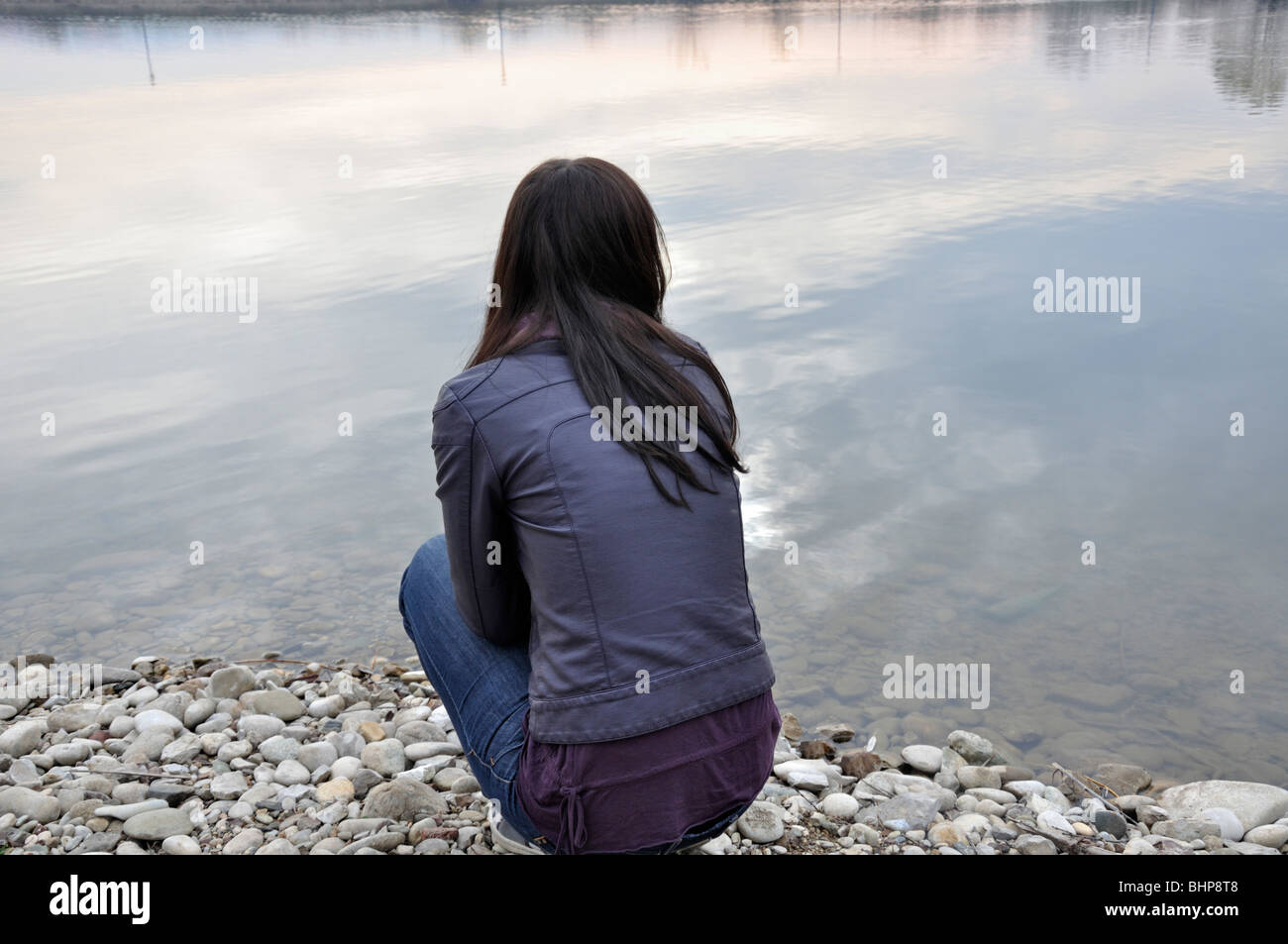 Woman kneeling by lake Stock Photo - Alamy