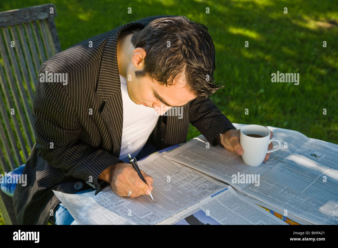 Young man reading the newspaper in the garden Stock Photo - Alamy