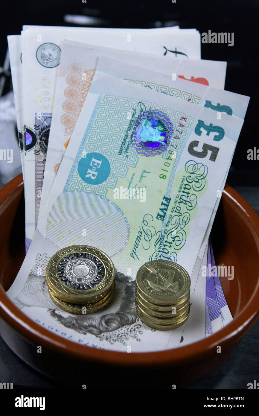 sterling notes and coins in a brown dish on an open book Stock Photo ...