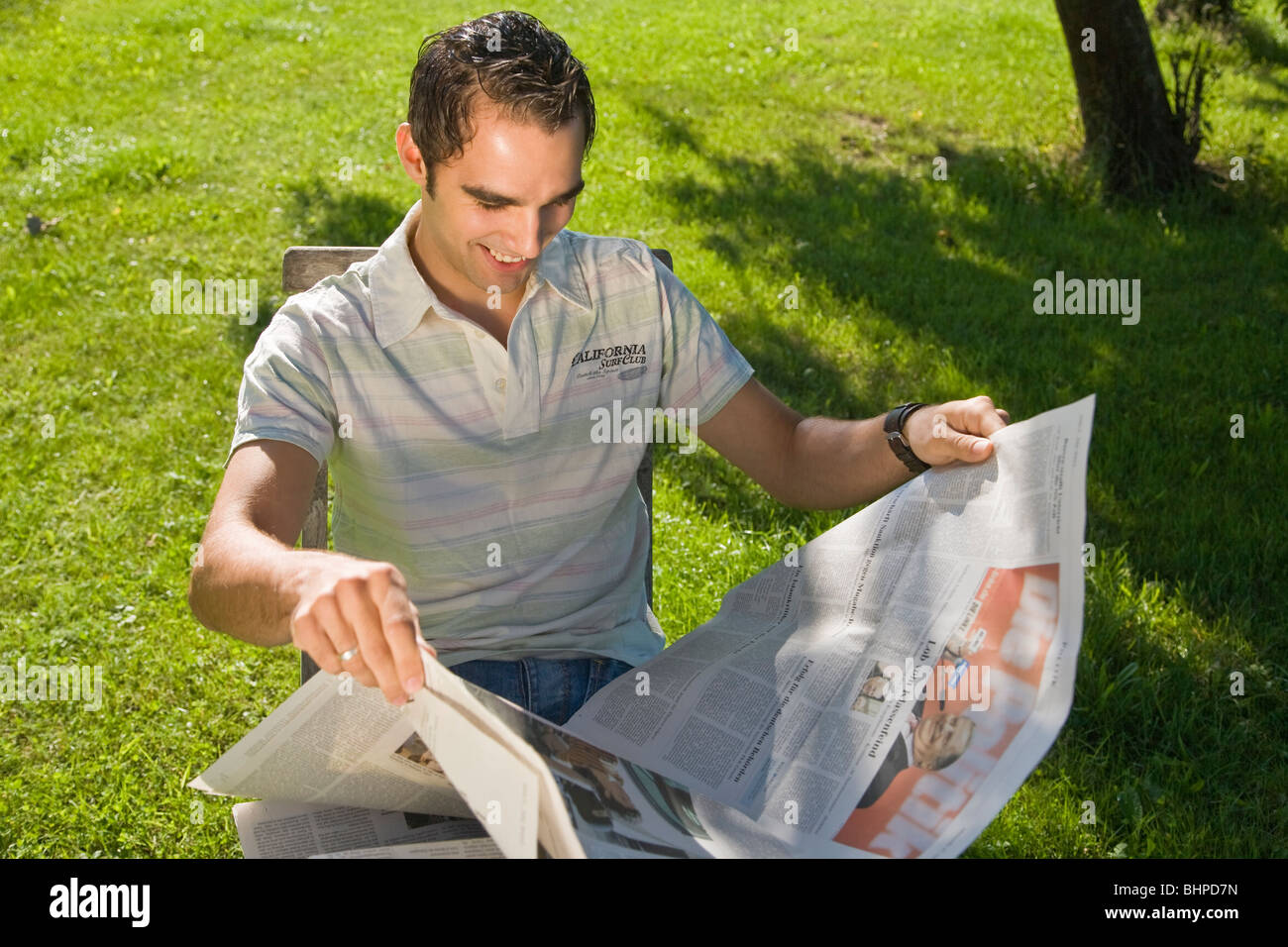 Young man reading the newspaper in the garden Stock Photo - Alamy