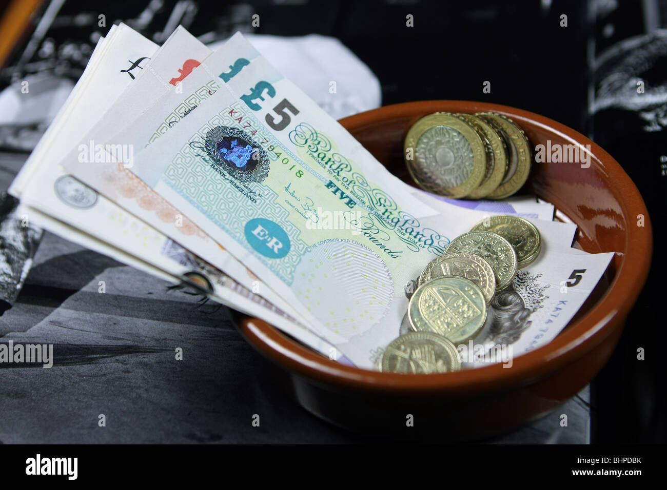 sterling notes and coins in a brown dish on an open book Stock Photo ...