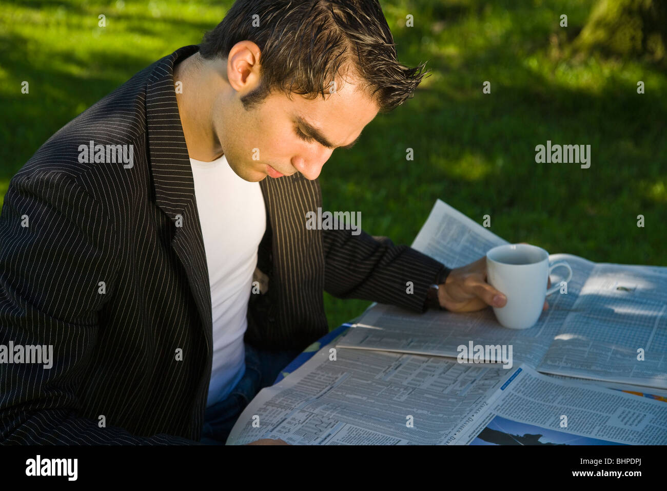 Young man reading the newspaper in the garden Stock Photo - Alamy