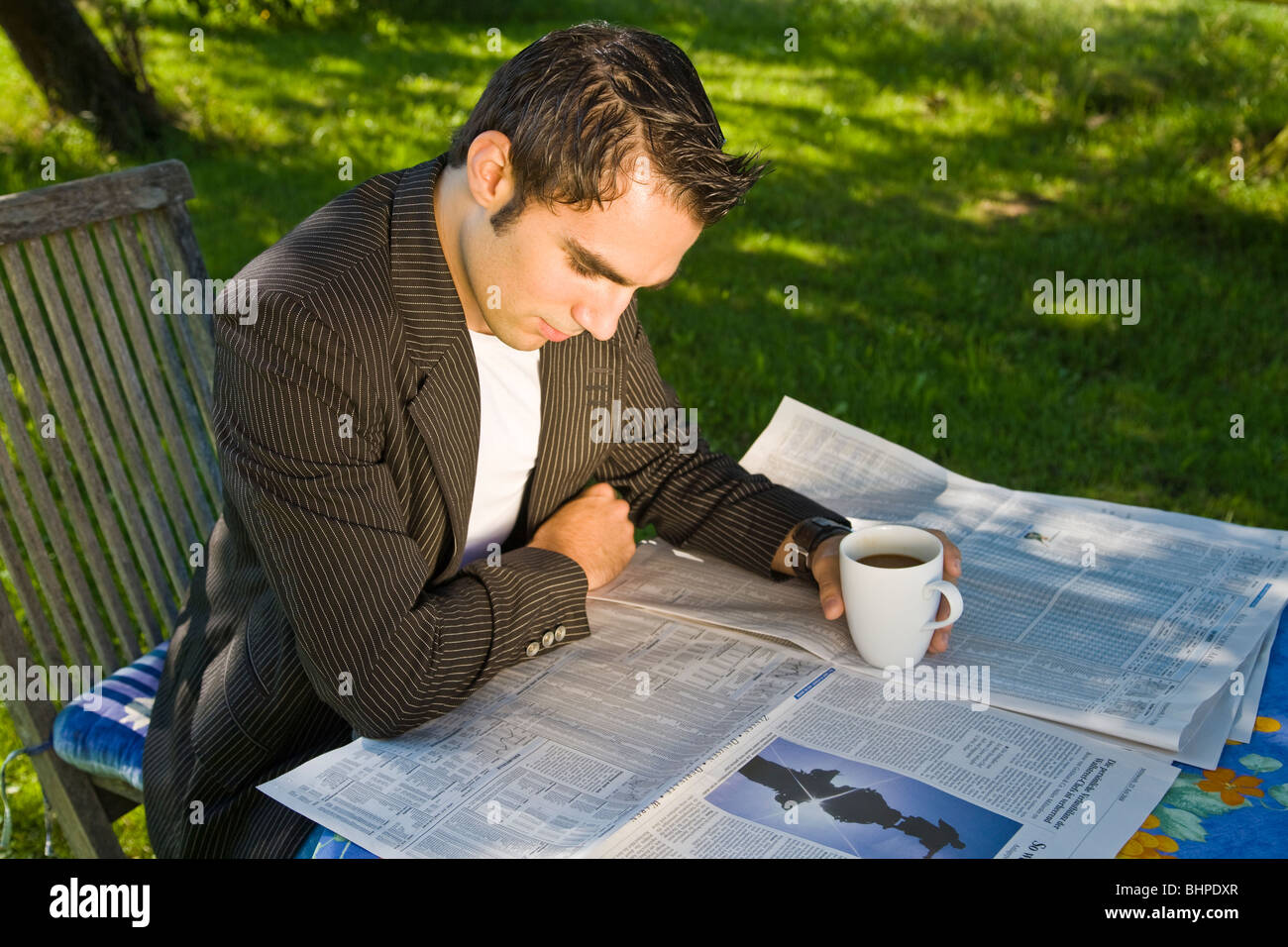 Young man reading the newspaper in the garden Stock Photo - Alamy