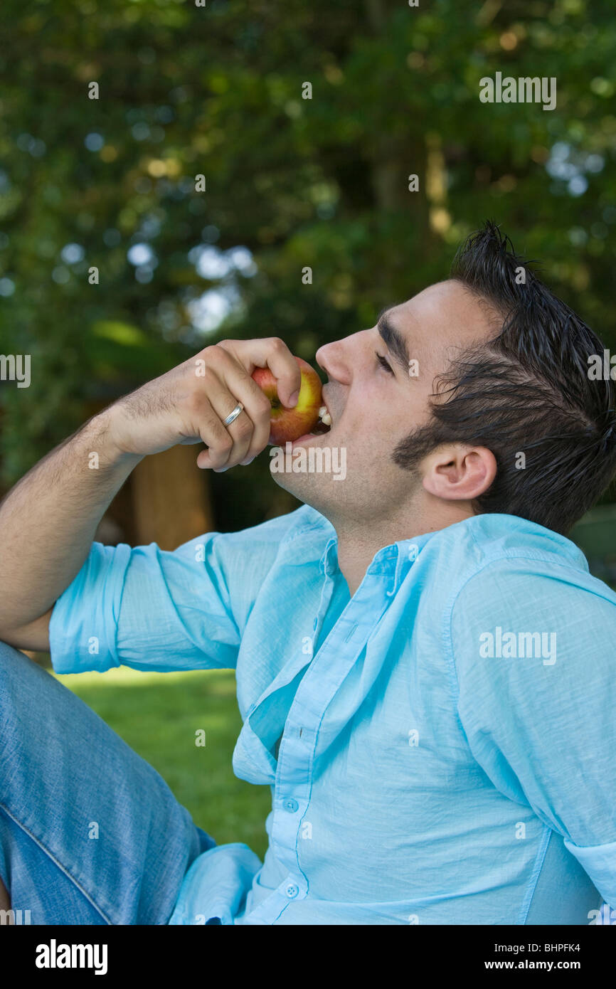 Young man eating an apple Stock Photo - Alamy