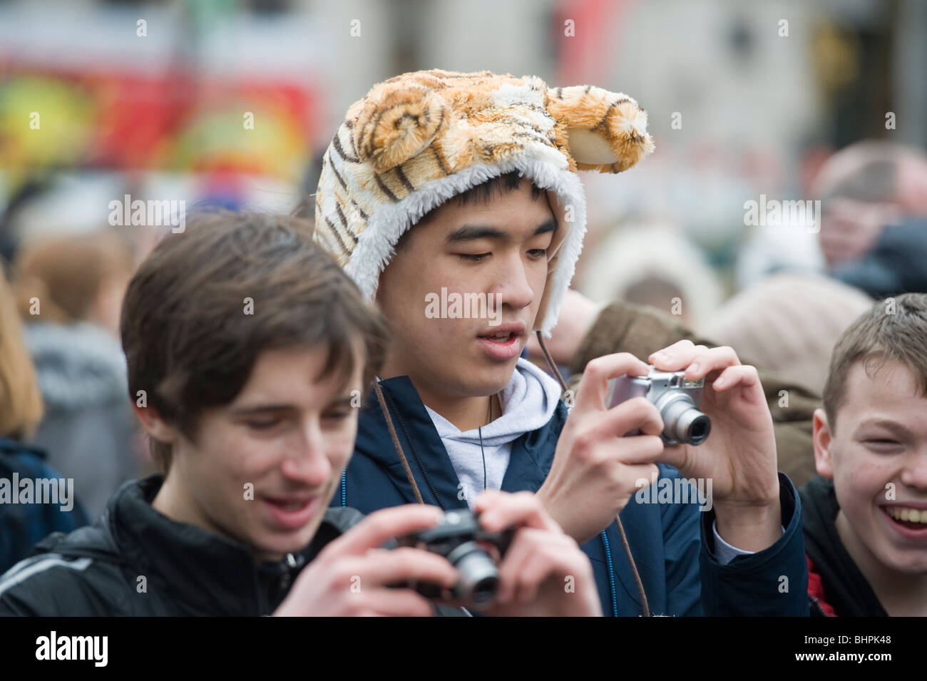 Two young men in a crowd of people looking at their cameras at Chinese ...